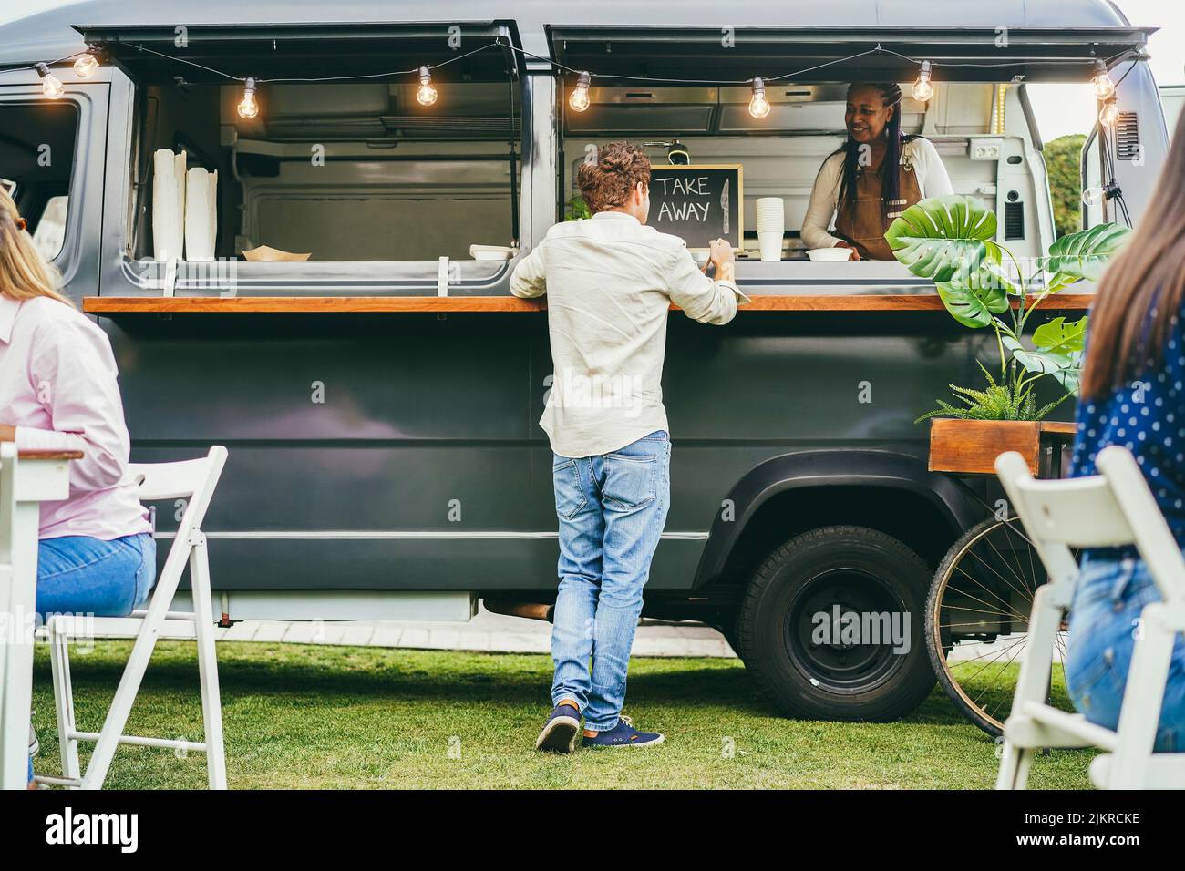 People eating at food truck restaurant outdoor - Focus on man back in ...