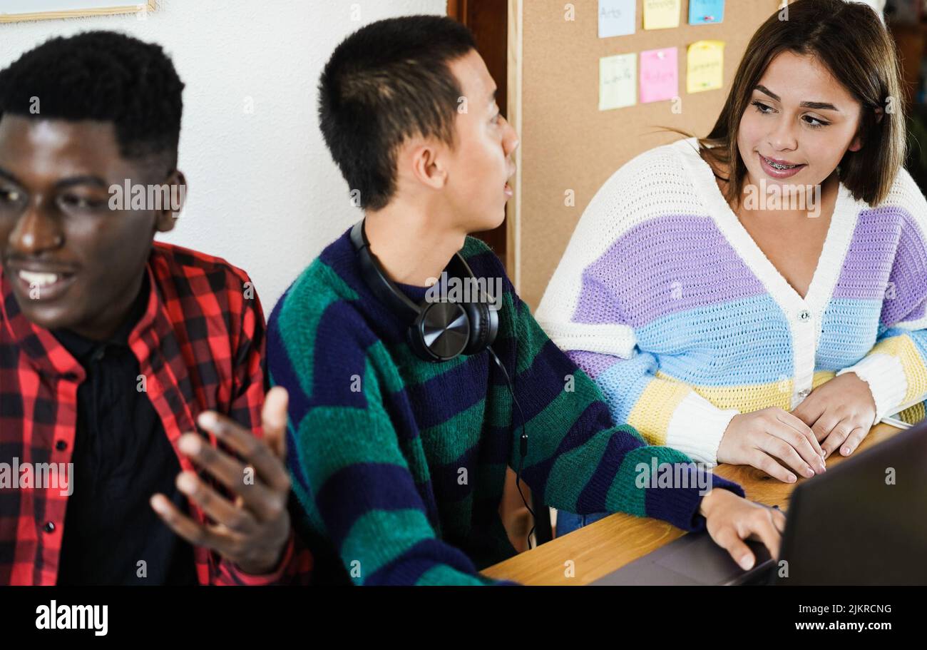 Multiracial students using laptop computer while studying together ...
