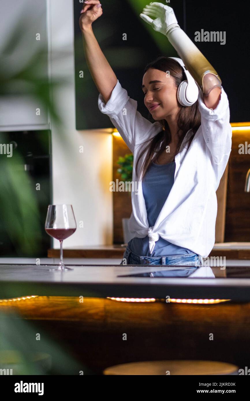 Happy girl with prosthetic arm listening music headphones and dancing ...