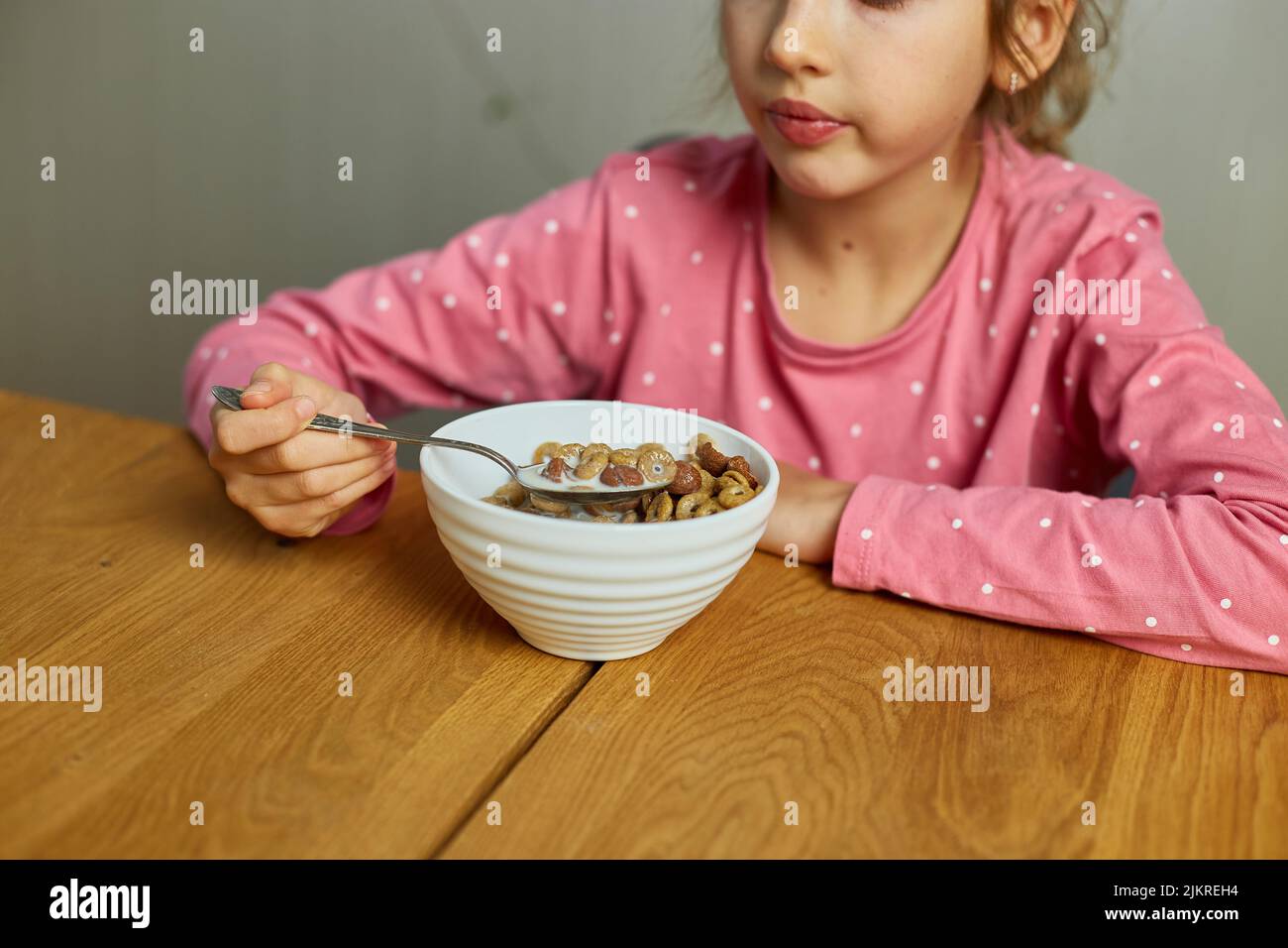 Cute little girl enjoy eating cereal with milk for morning breakfast ...