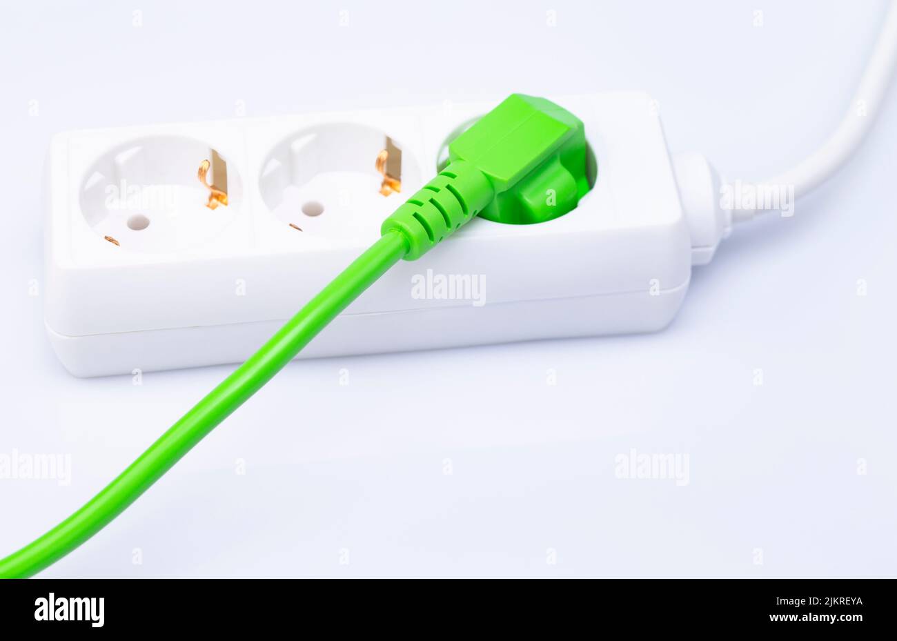 The photo shows a multiple socket with a green power cable isolated on ...