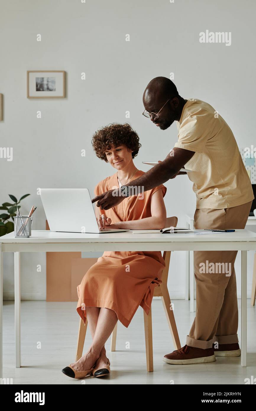 African businessman pointing at monitor of laptop and discussing online ...