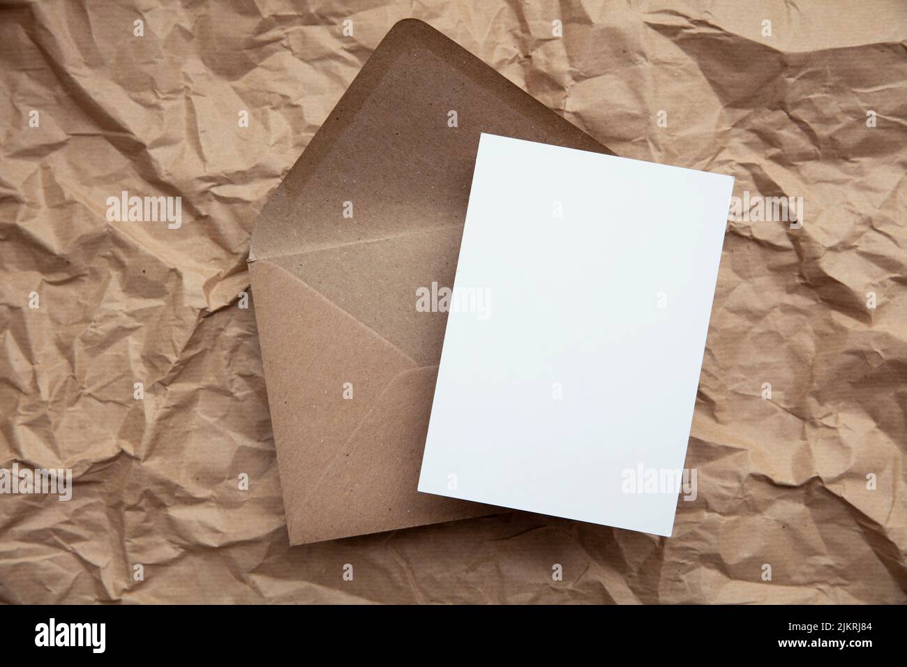 Blank card with kraft brown paper envelope template mock up on crumpled ...