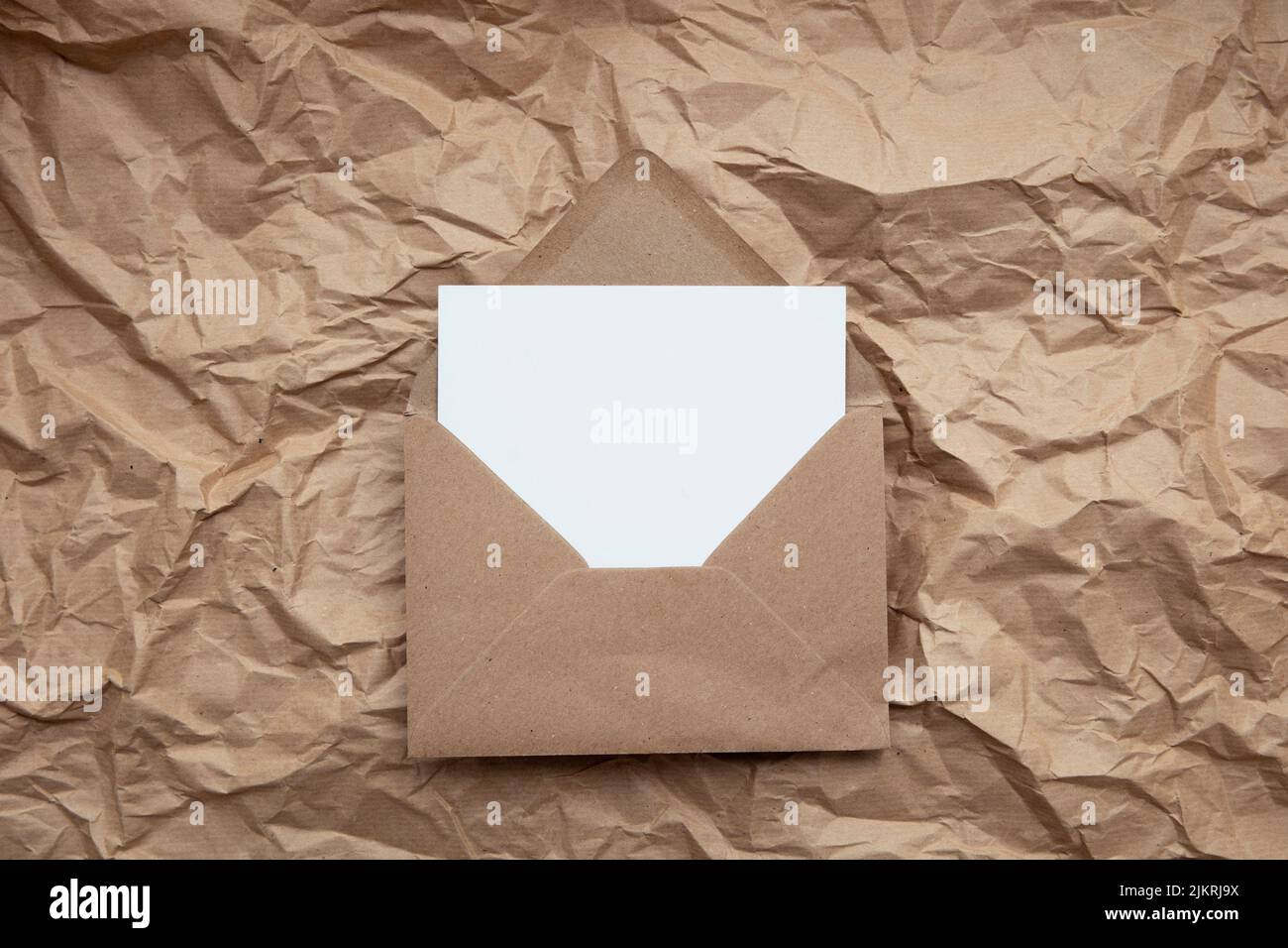 Blank card with kraft brown paper envelope template mock up on crumpled ...