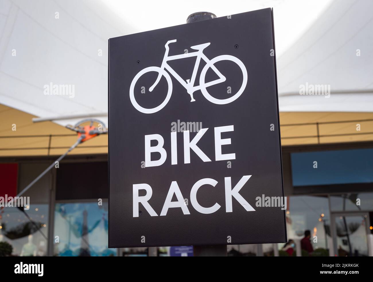 Black and white bike rack sign close up in busy urban shopping area ...