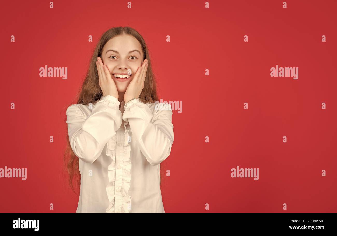 amazed child hold face express positive emotions on red background copy ...