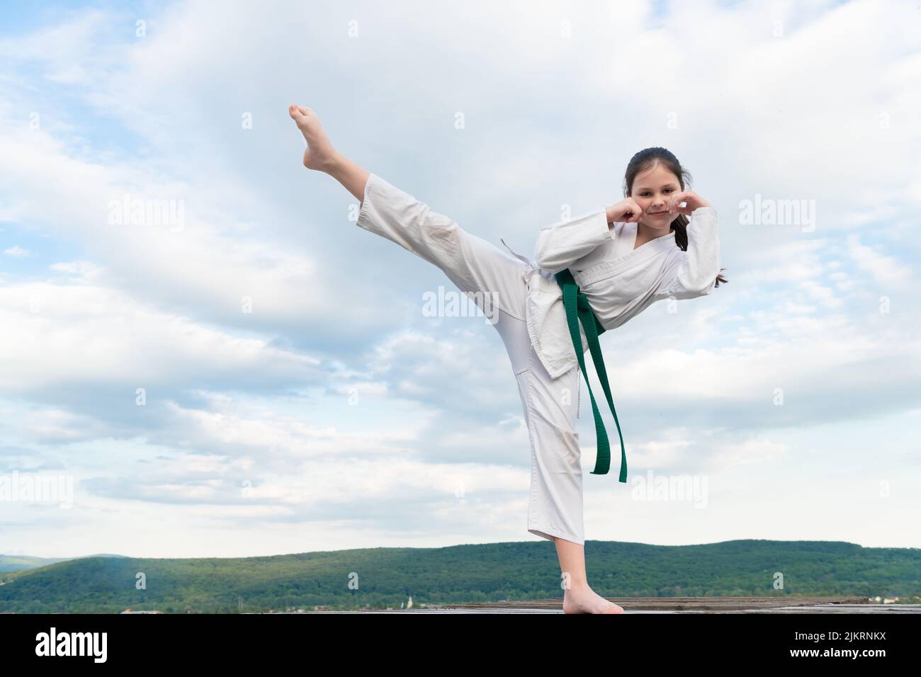 teen girl practicing karate. teen child fighter on sky background. teen kid practicing kick in ...