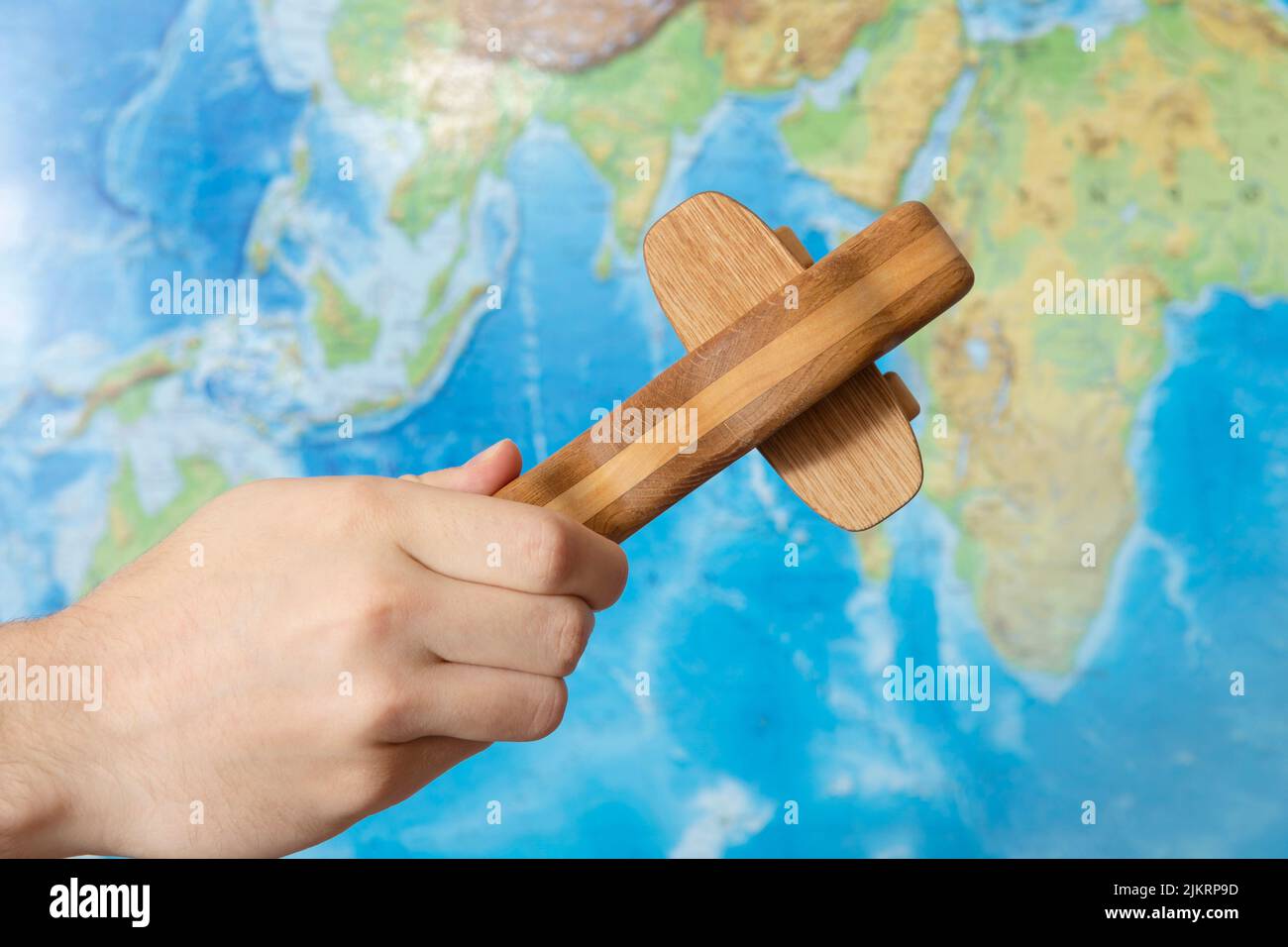 A man's hand holds a wooden toy model of an airplane against the ...