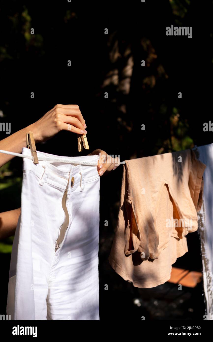 Close up view of unrecognizable woman hanging out fresh washed clothes ...