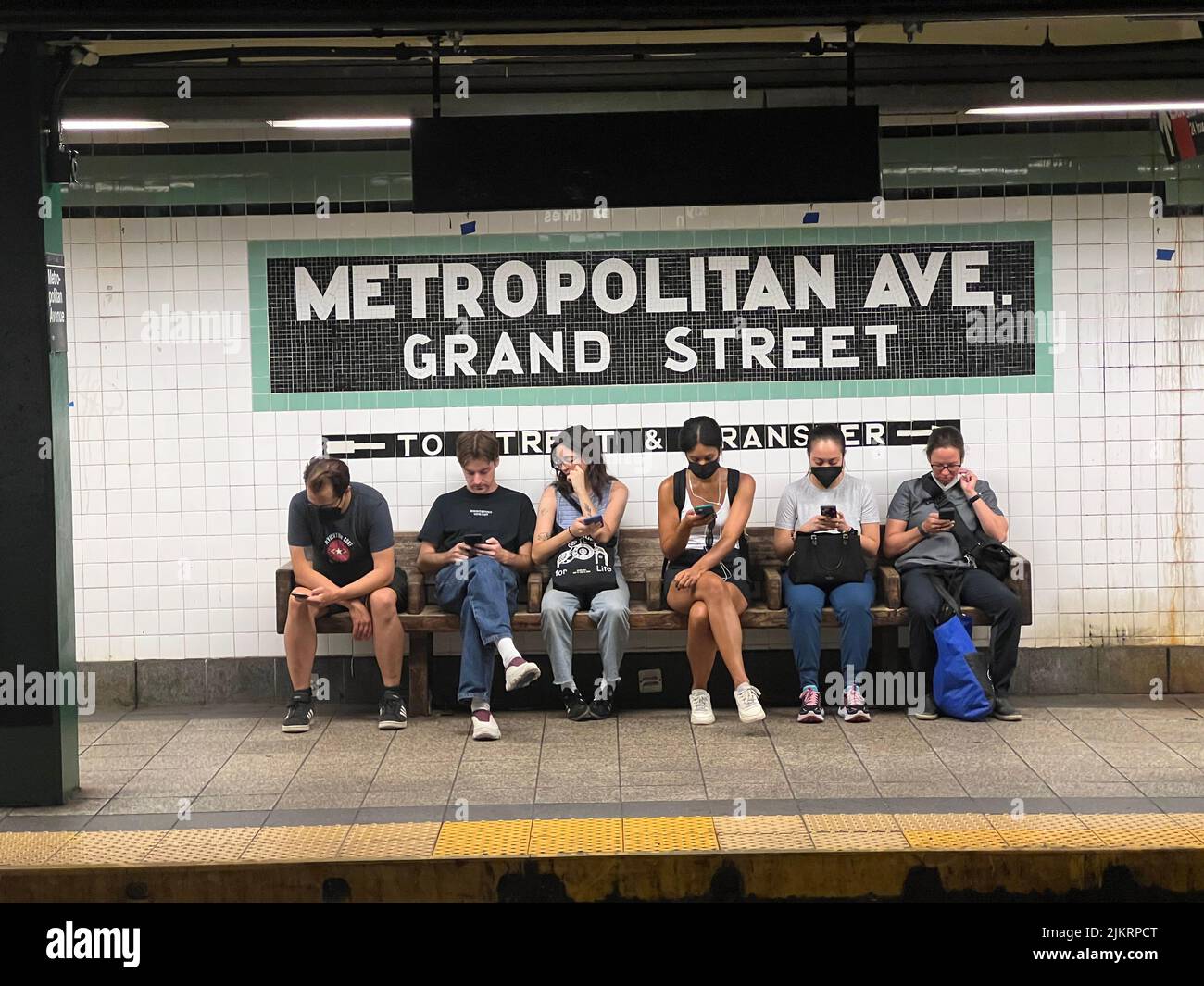 People wait with their phones for a Queens bound G Train at the ...