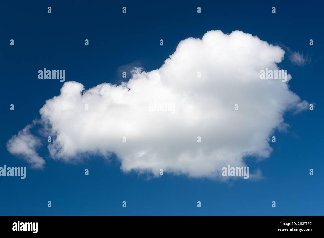 A white cumulus cloud against a dark blue daytime sky. A high ...