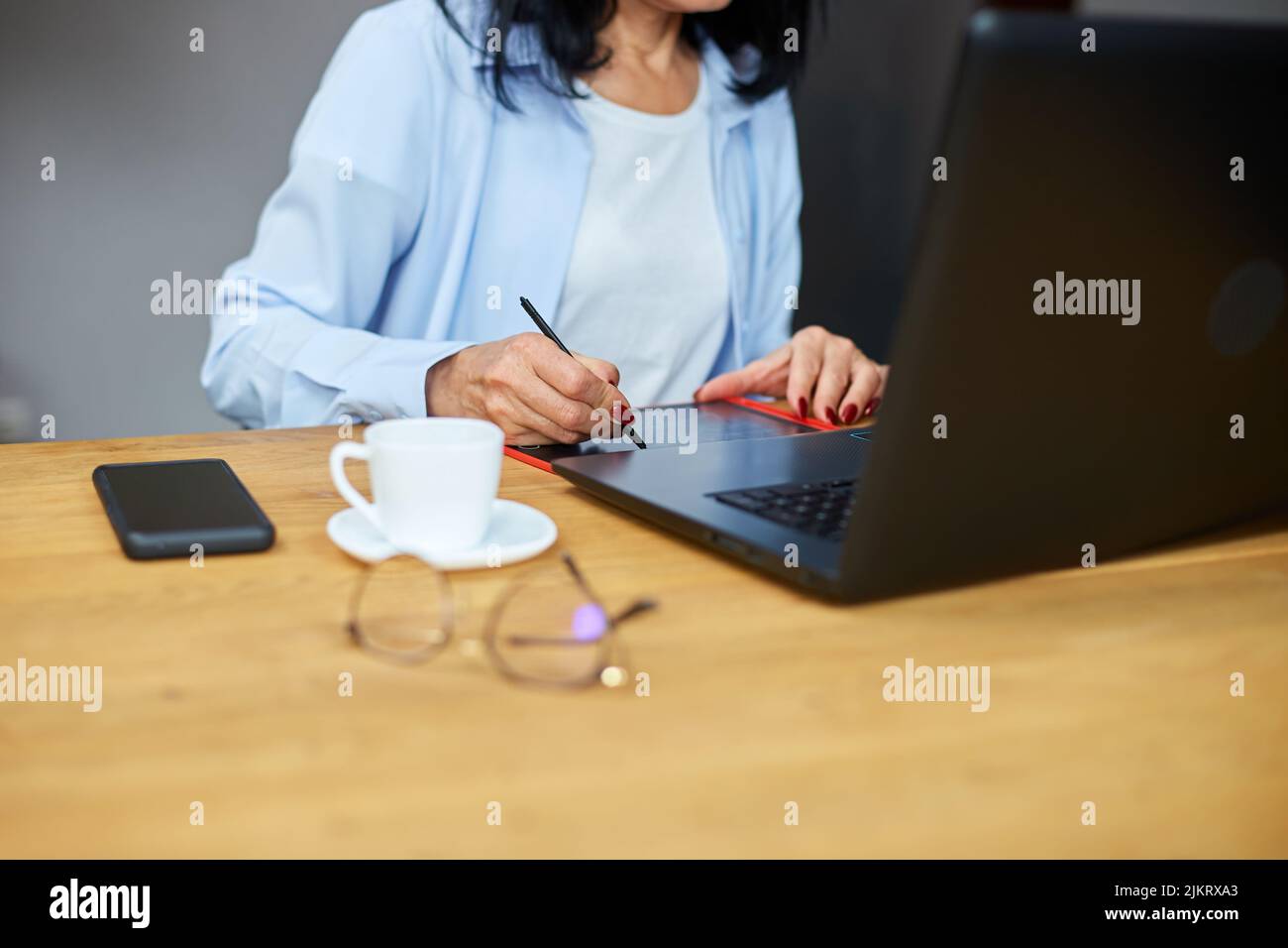 Senior woman designer using graphics tablet and stylus, working at ...