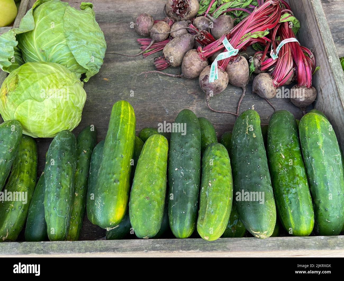 Colorful cabbage, turnips, and cucumbers at a fruit and vegetable stand ...