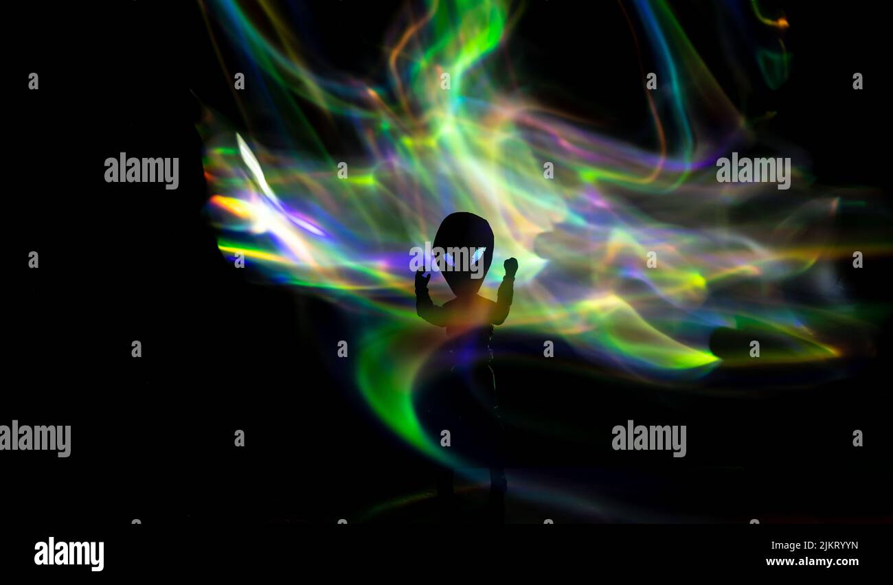 Alien-looking humanoid figure among multi-colored lights. Alien life ...