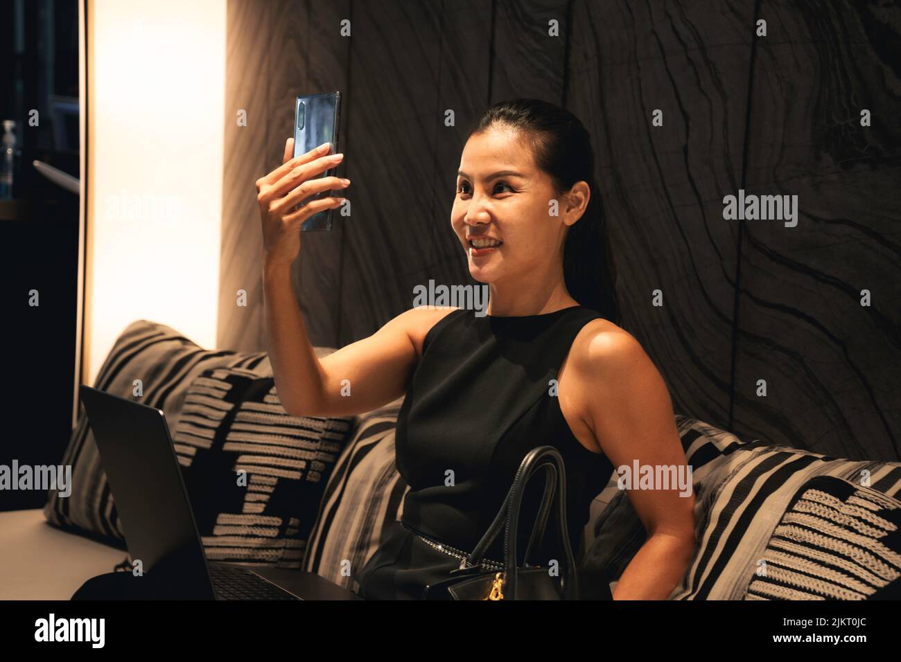 Business woman using a mobile phone and a laptop to work online Stock ...