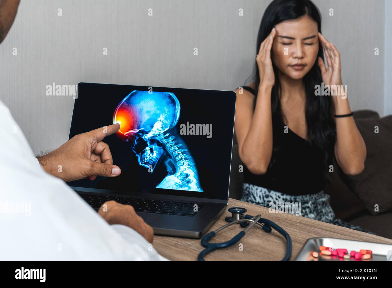 Doctor showing a x-ray of pain in the brain on a laptop. Migraine ...