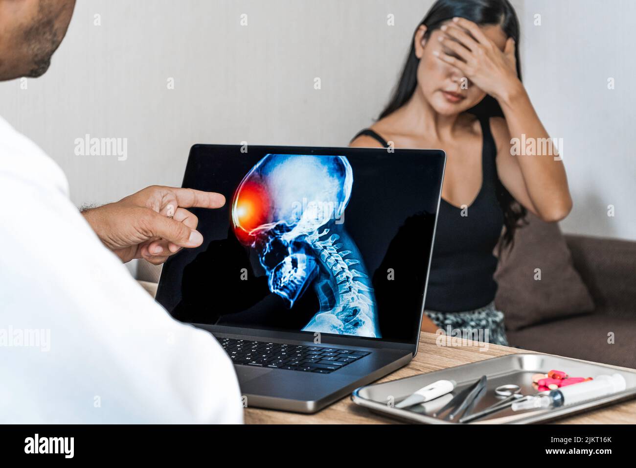 Doctor showing a x-ray of pain in the brain on a laptop. Migraine ...