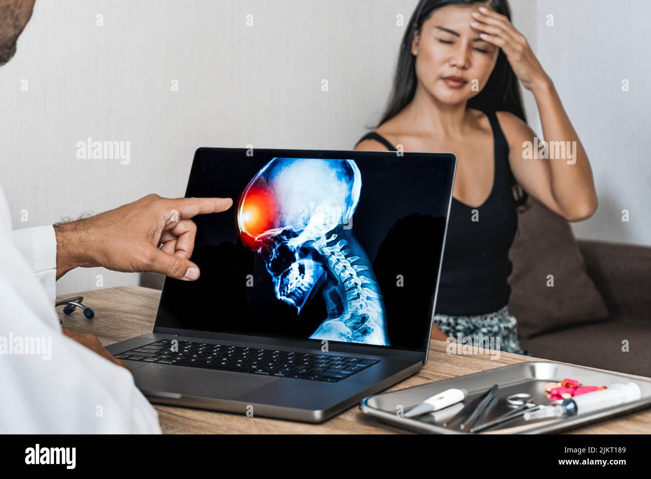 Doctor showing a x-ray of pain in the brain on a laptop. Migraine ...