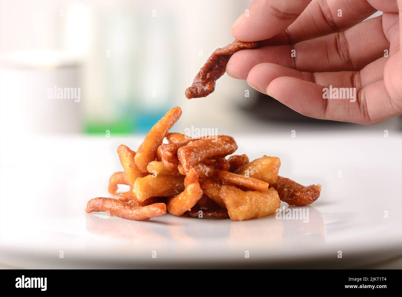 hand taking a piece of savory and crunchy snack coated with sugar syrup ...