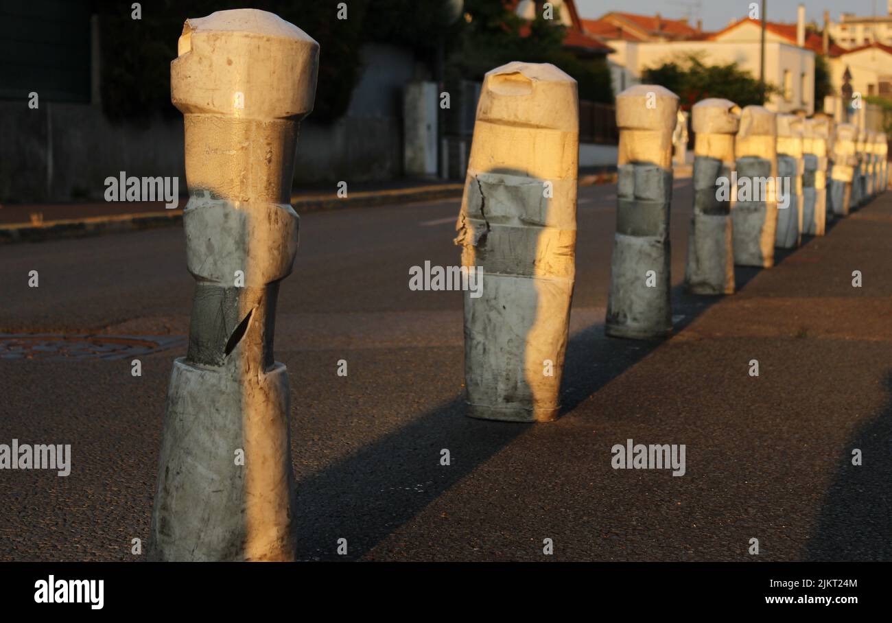 White plastic permanent bollards at sunset. Badly scratched up and hit ...