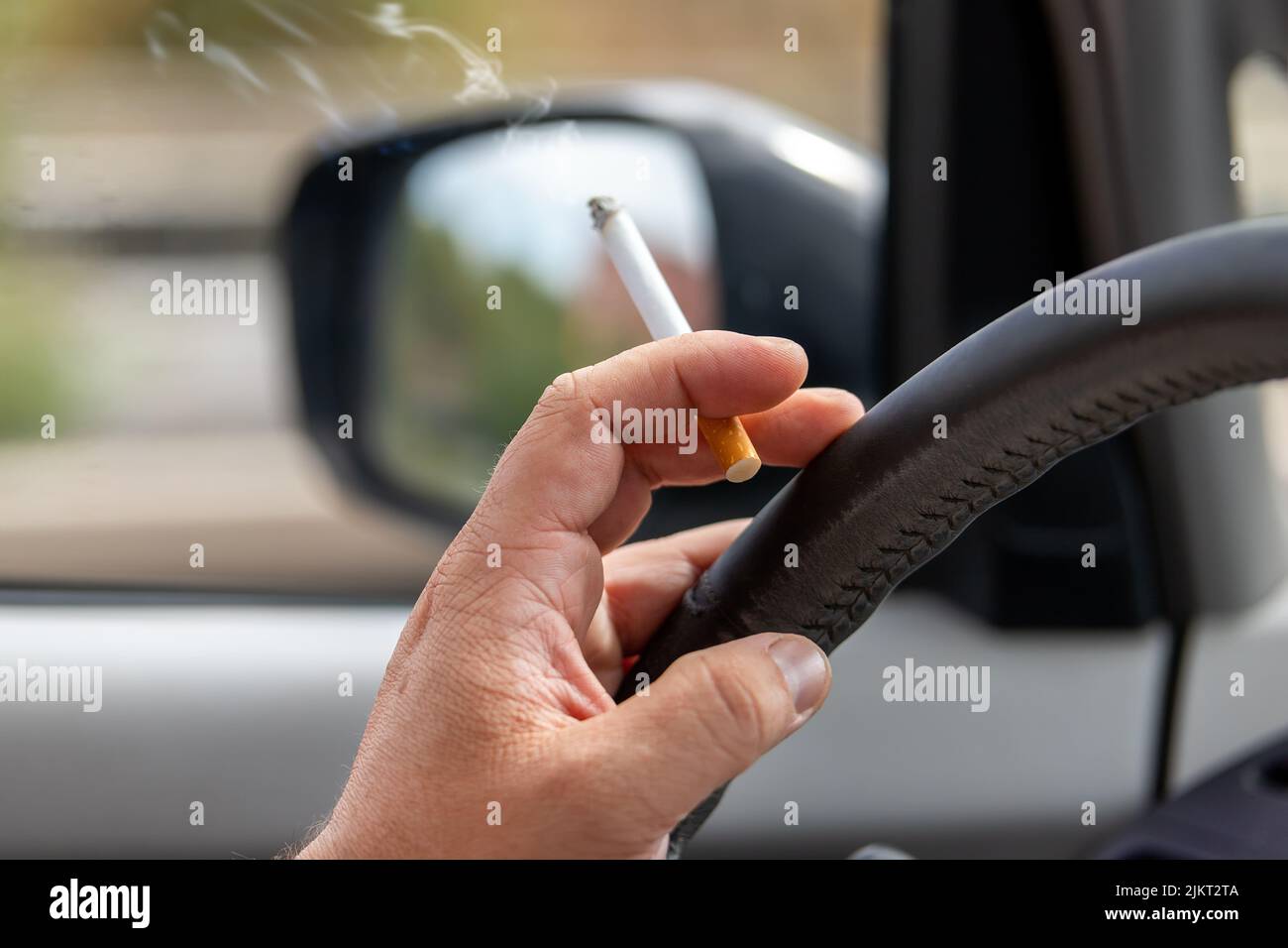 Close-up detail view of male hand driver holding cigarette while ...