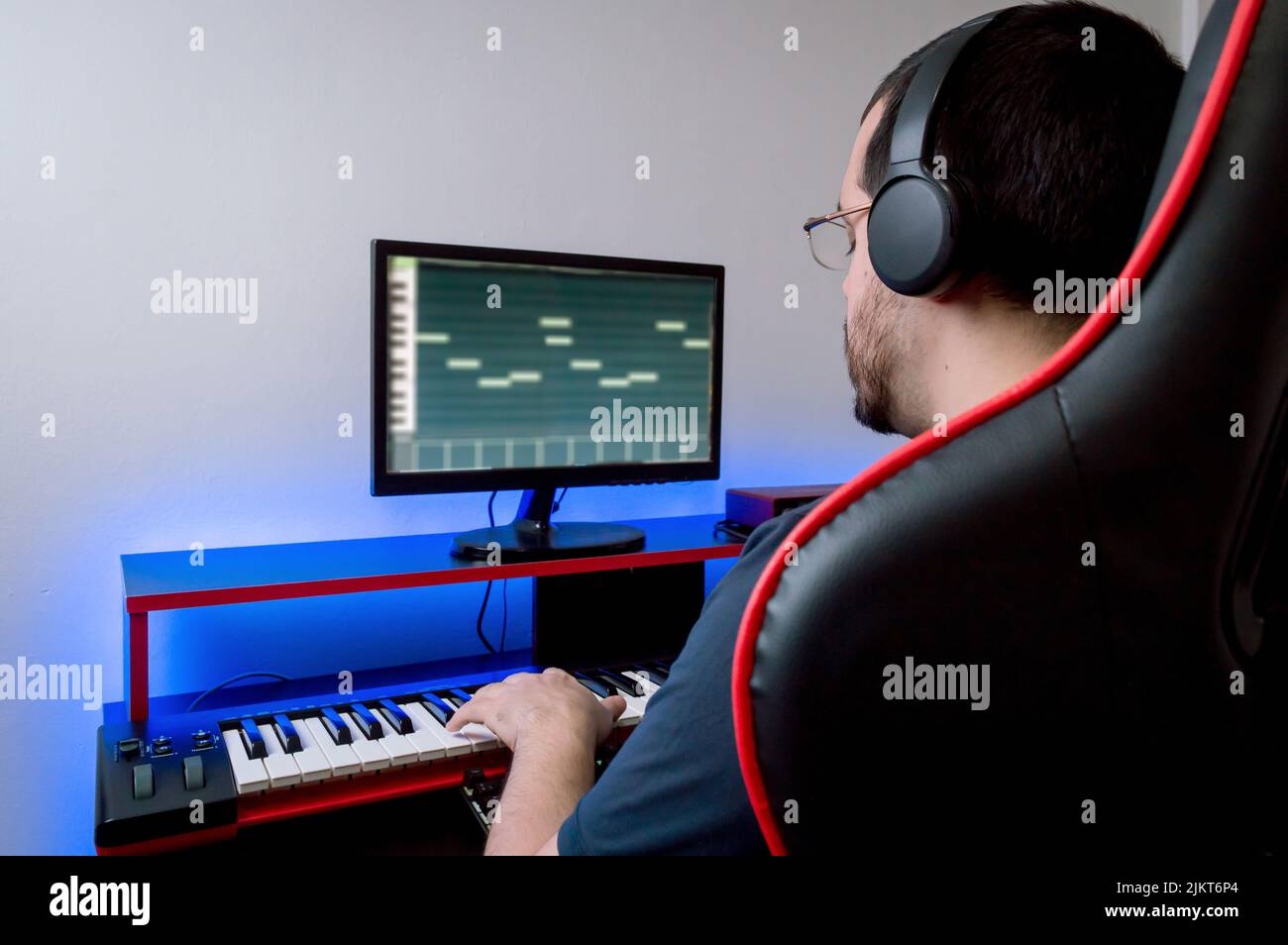 side view young caucasian man with headphones, sitting in his home ...