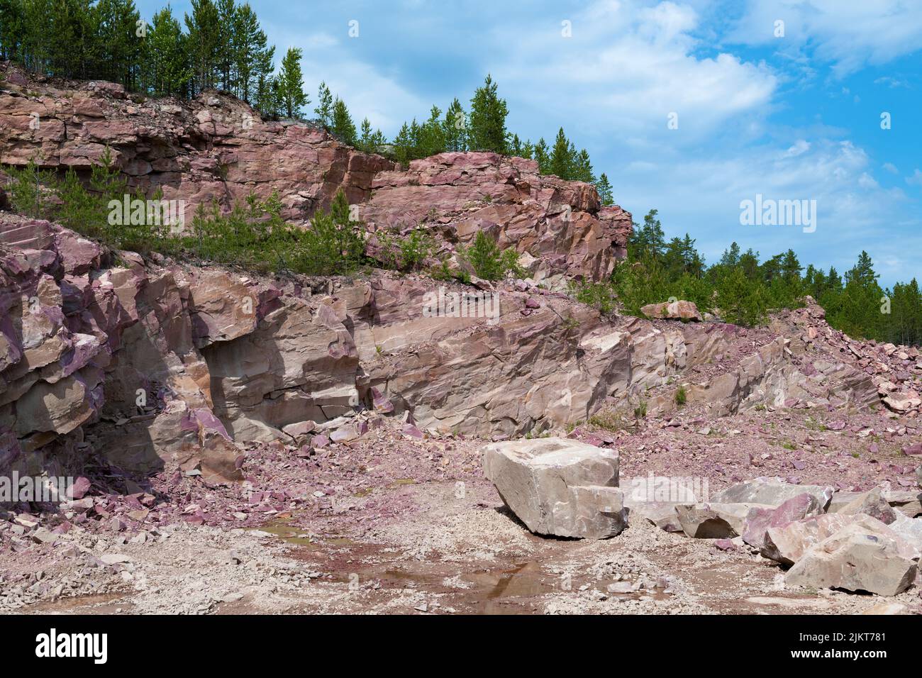 June sunny day in a old quarry for the extraction of crimson quartzite ...