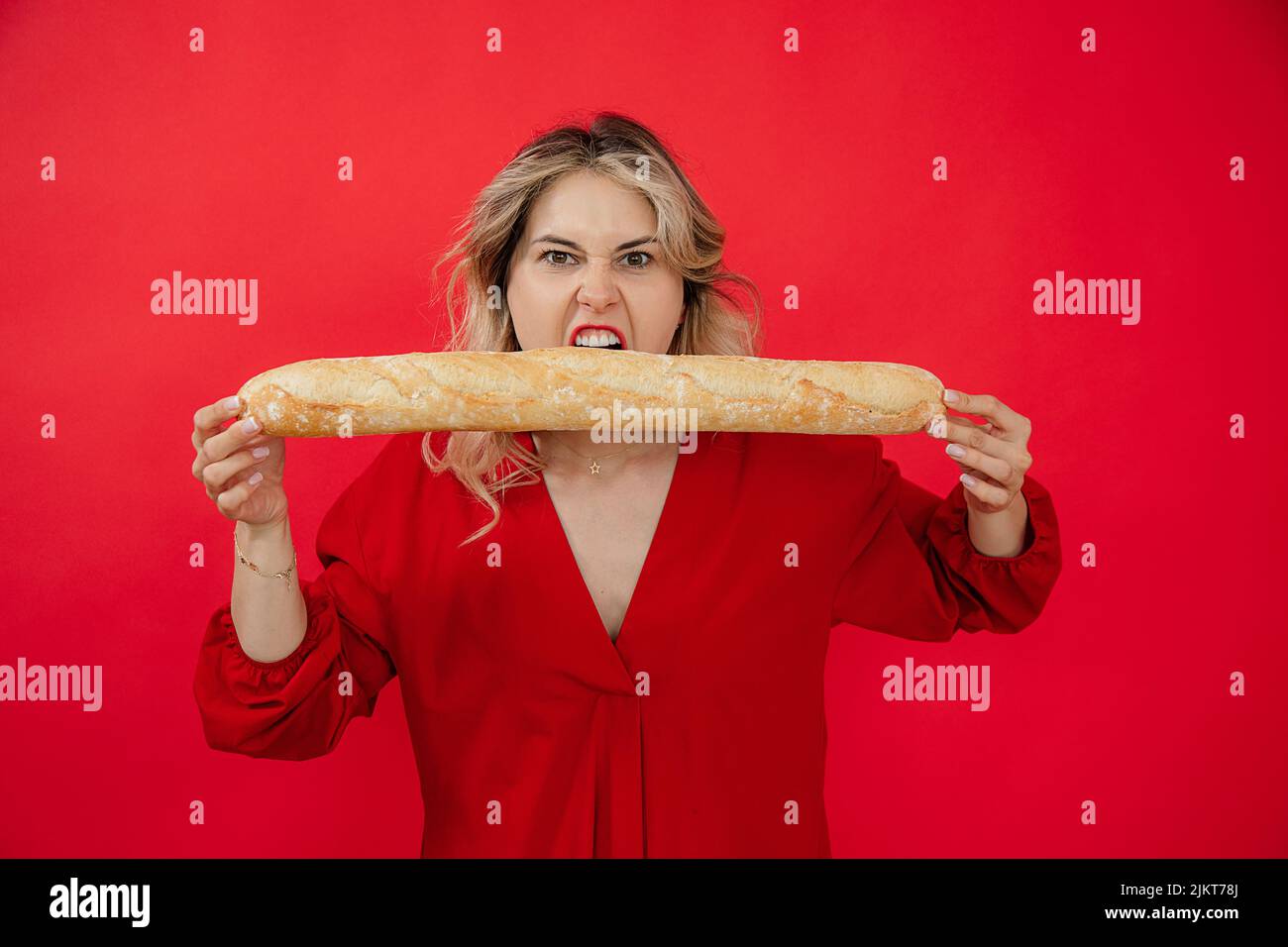 Hungry aggressive blond woman in red dress holding biting long french ...