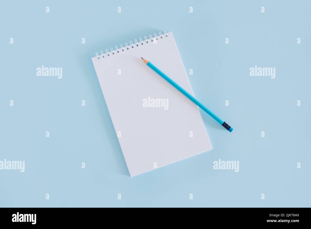 Notebook with blank page and pencil on light blue background. Flat lay ...