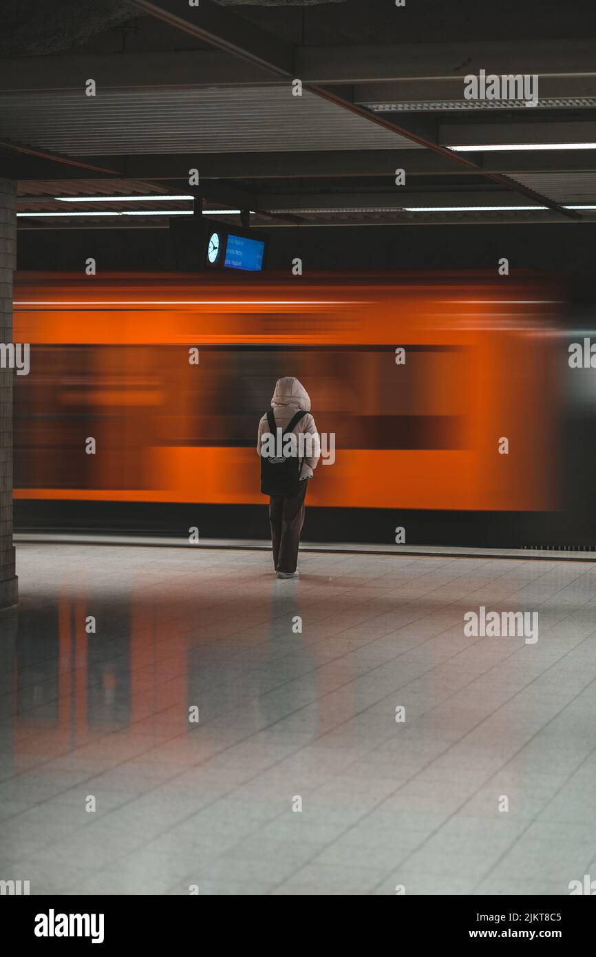 A rear view of a female watching Helsinki metro train leaving the ...