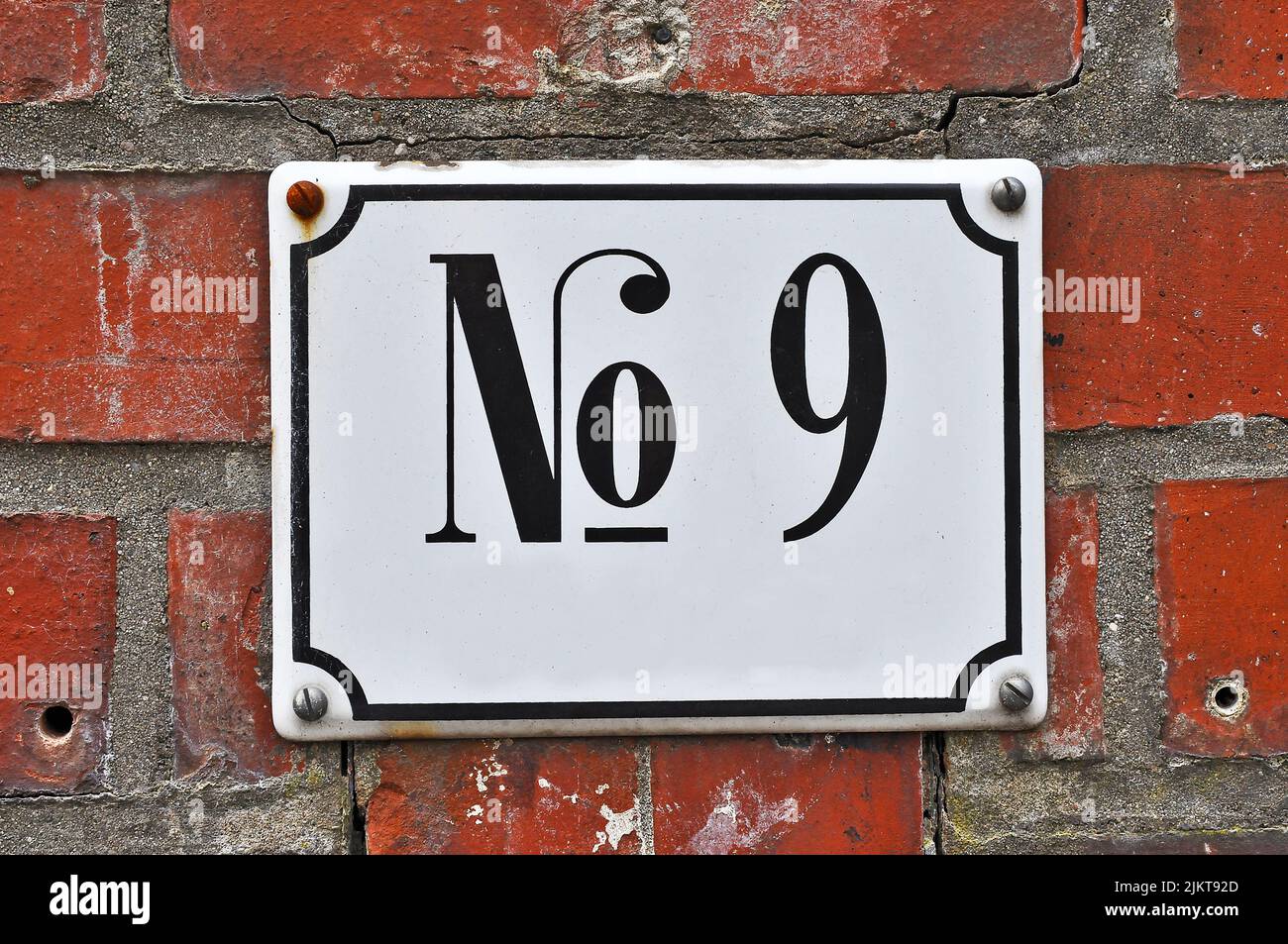 A sign with the number 9 hanging on a brick wall Stock Photo - Alamy