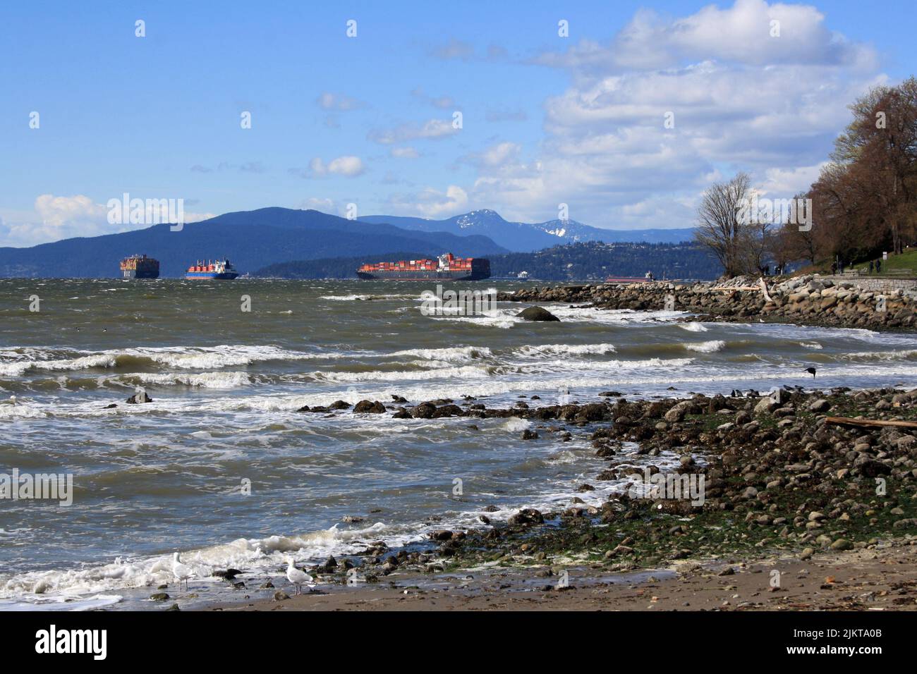 A beautiful view of the ocean waves hitting the rocky English Bay Beach ...