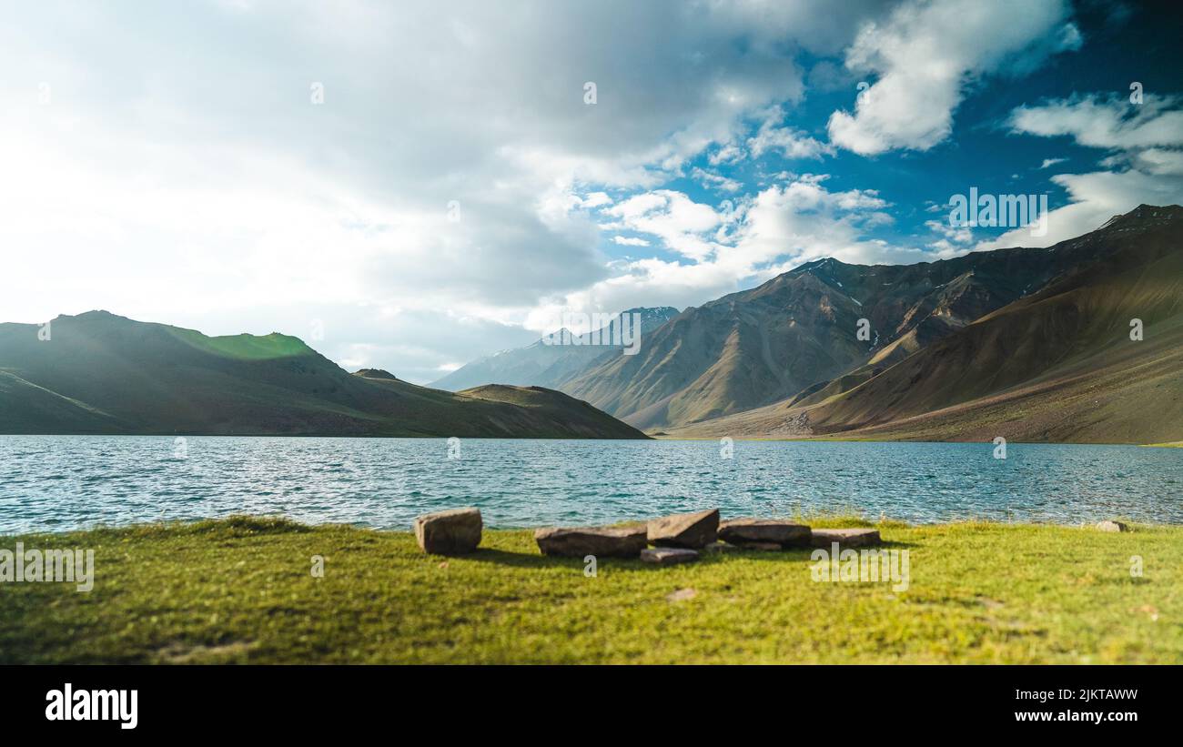 The Chandratal lake, over a background of tall mountains, under a ...