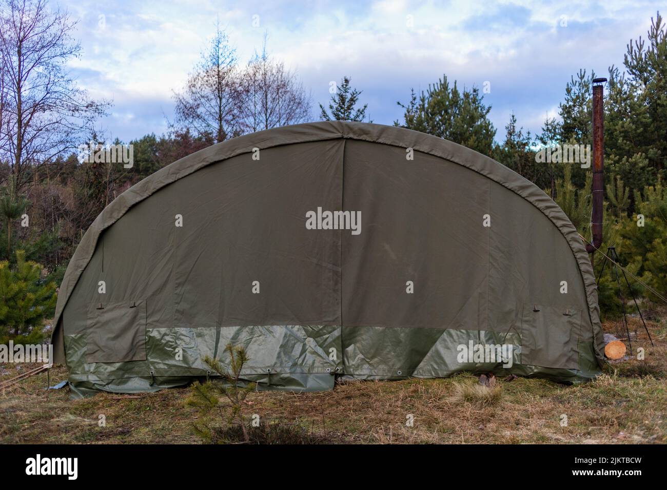 A beautiful shot of a camp tent on the ground with trees aligned with ...