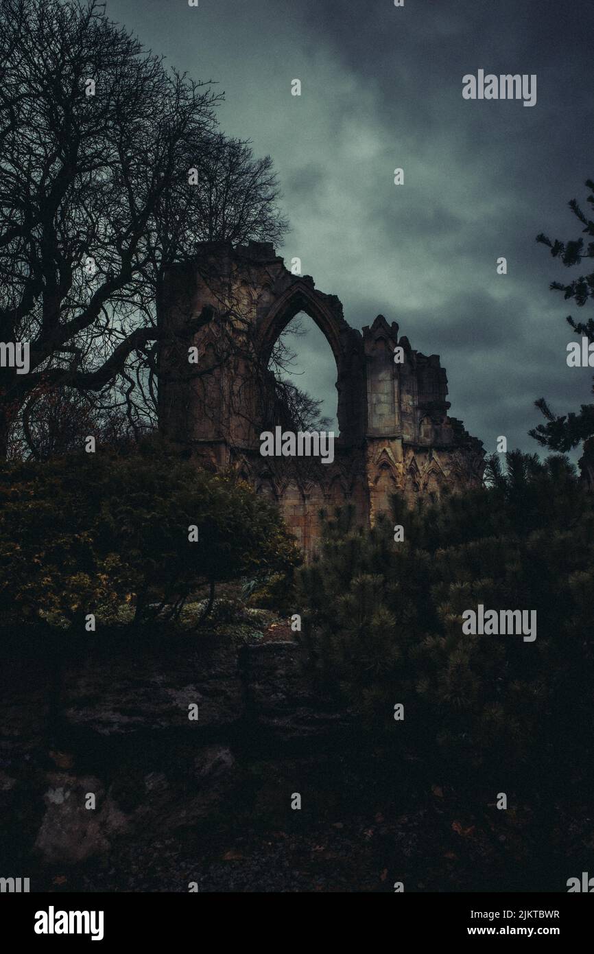 A beautiful view of cathedral ruins with a garden under the cloudy sky ...