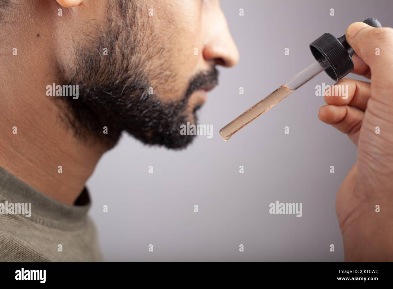 oung handsome guy showing a dropper filled with beard oil and going to ...
