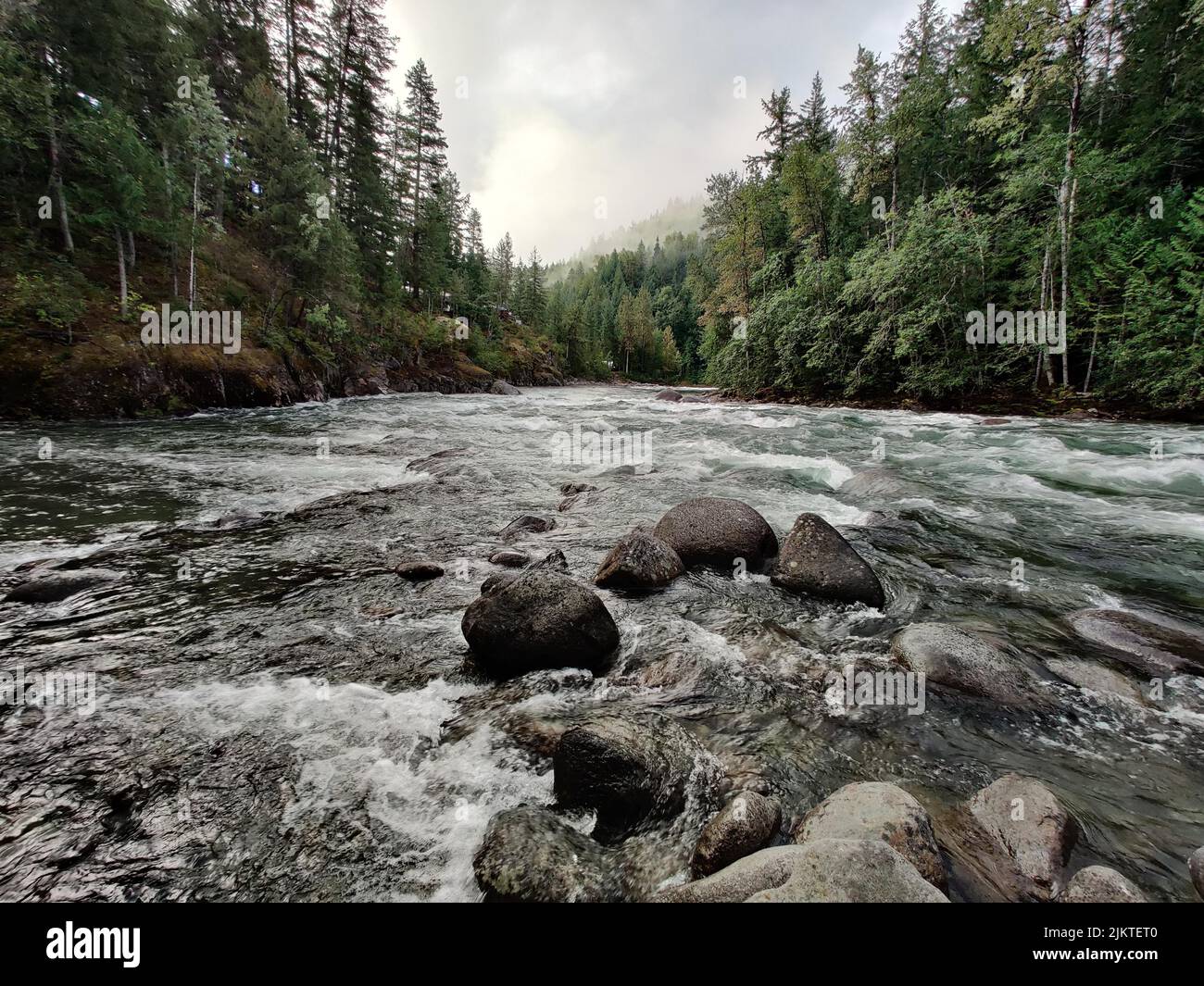 The rocks in Fraser River, Boston Bar with trees and cloudy sky in ...