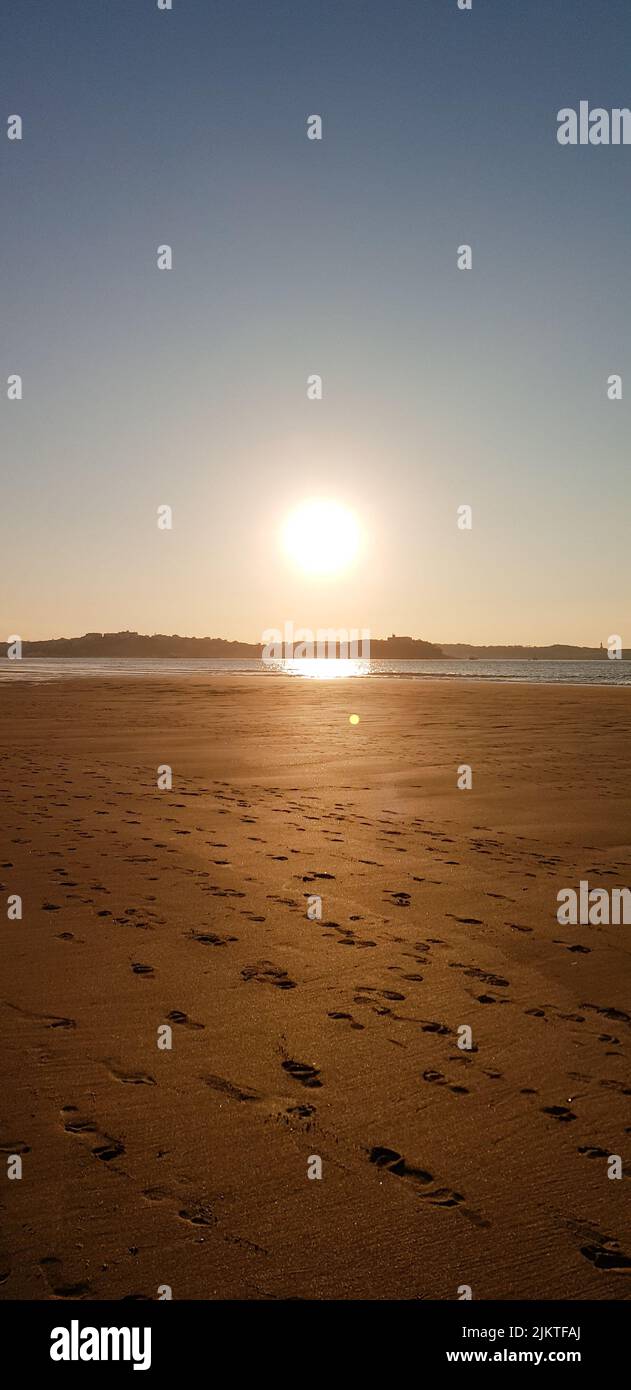 A vertical view of the footprints on the beach with the birght sun ...