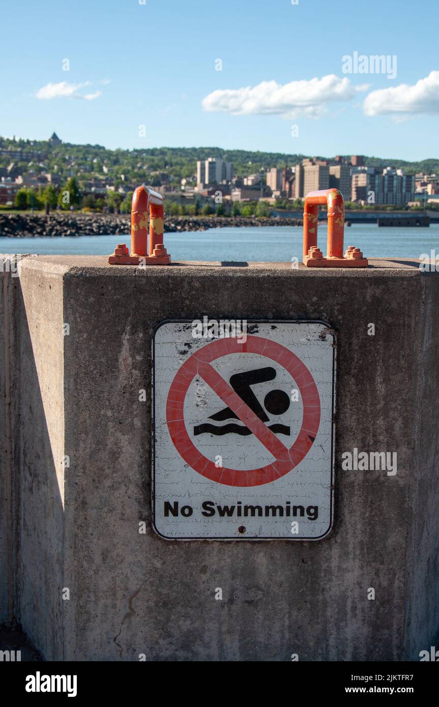 A vertical shot of a No swimming sign in front of a lake in a city ...