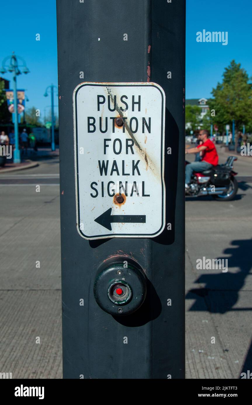 A vertical shot of a metal sign with Push button for walk signal and a ...