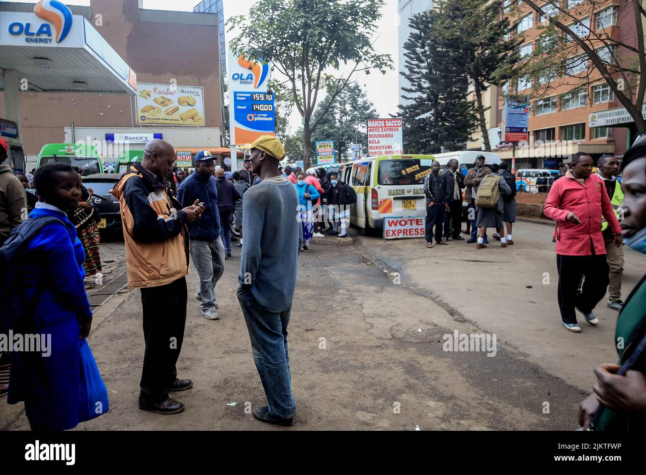 Pedestrians and students wait at a busy busy bus terminal in Nairobi ...