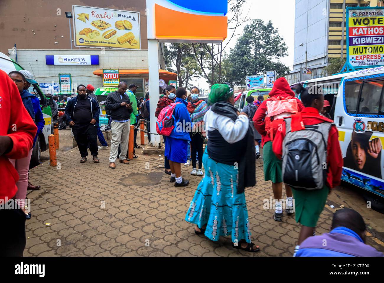 Pedestrians and students wait at a busy busy bus terminal in Nairobi ...