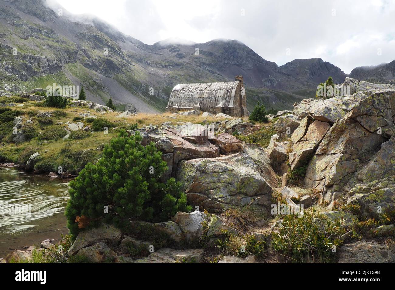 A scenic view of a stone building on a bank of a river against rocky ...