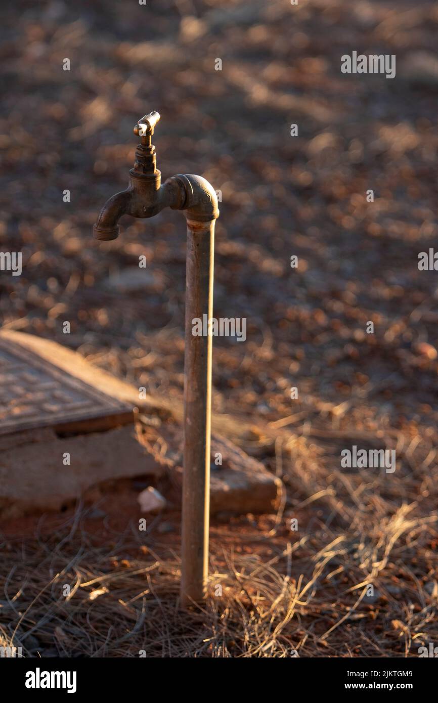 A vertical closeup of an old rustic tap on the ground in sunlight Stock ...