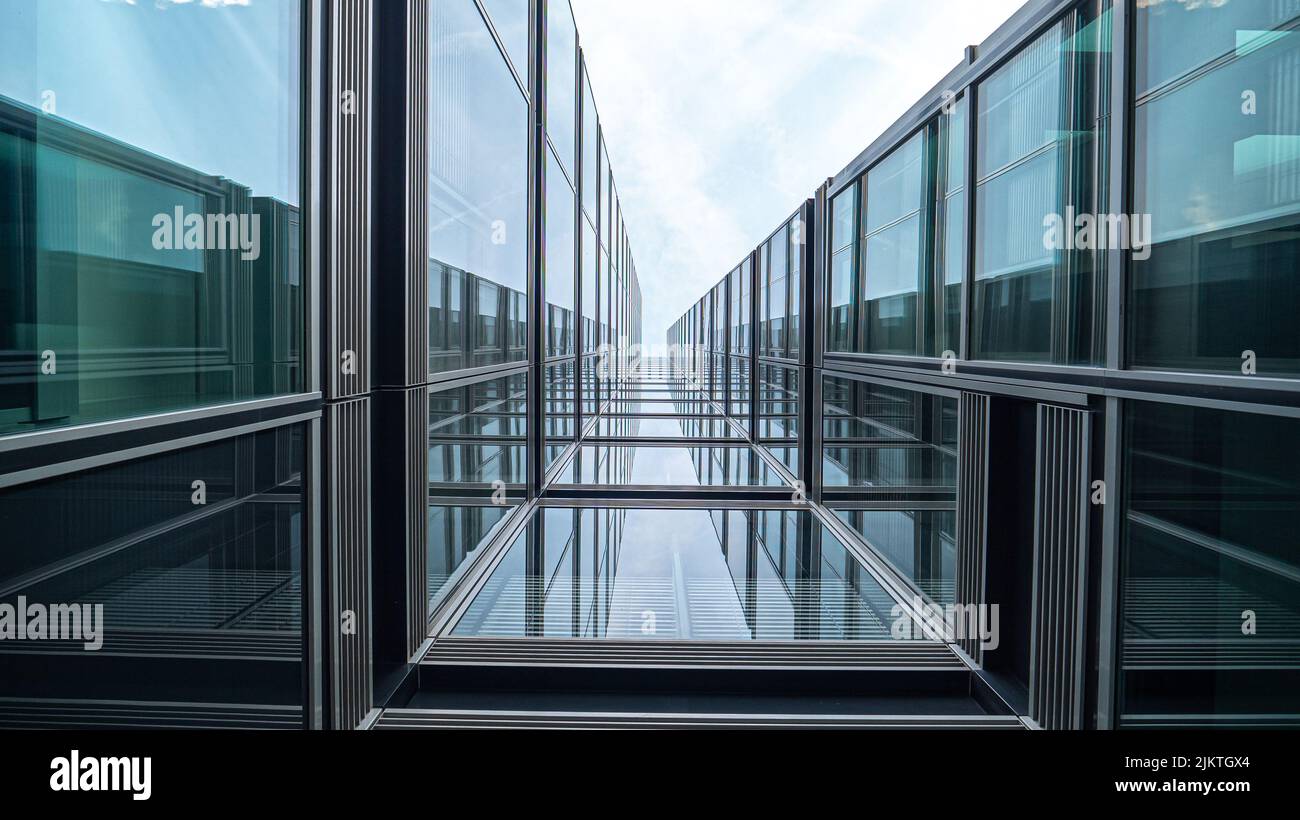 A low-angle shot of a modern glass building rising up to the blue sky ...