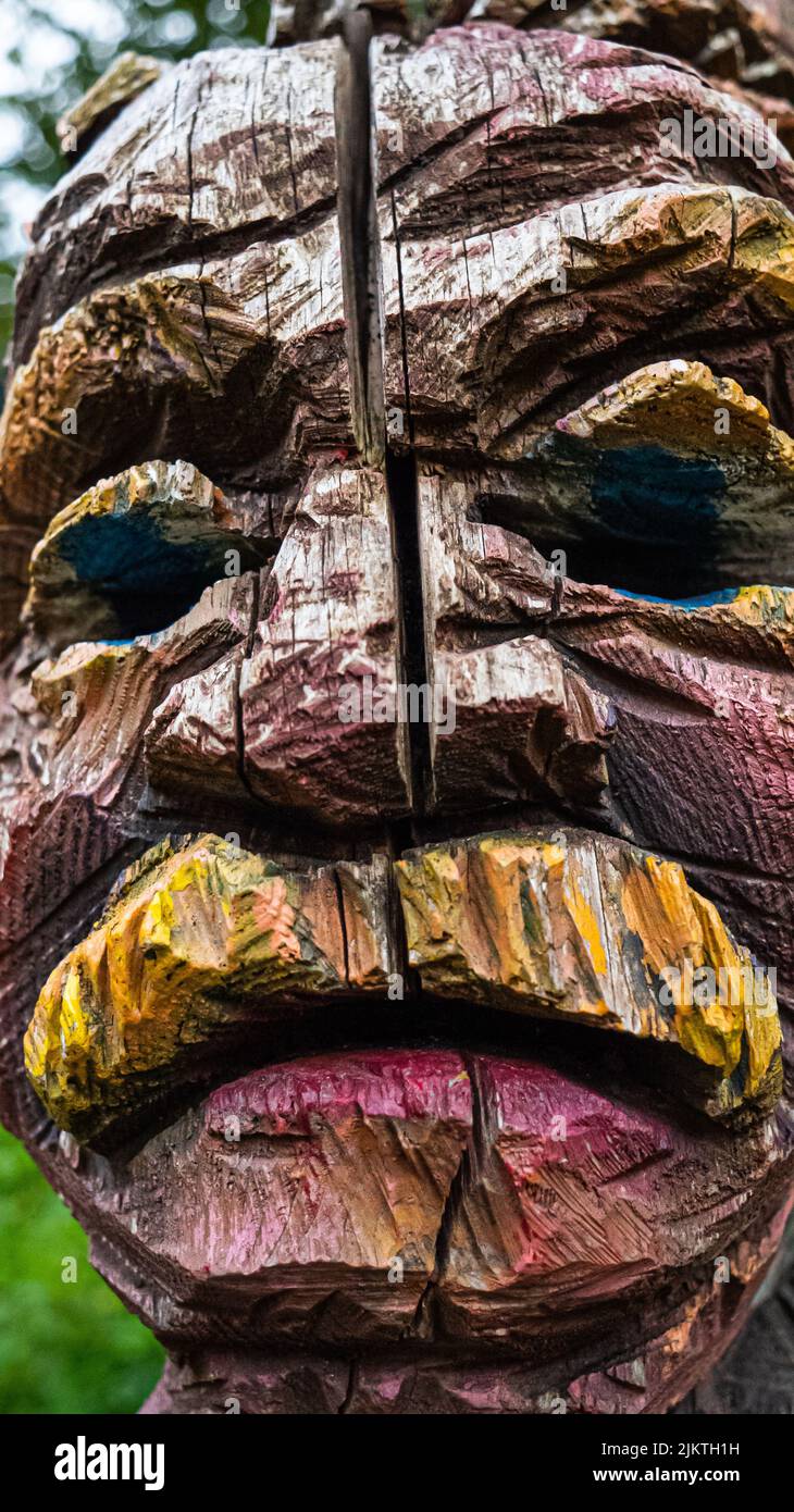A vertical shot of a face carved from wood with different colors in a ...