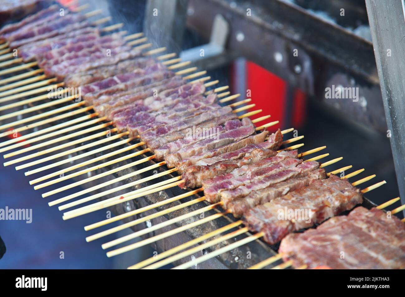 The skewers of lamb arrosticini cooking on a charcoal grill barbecue ...