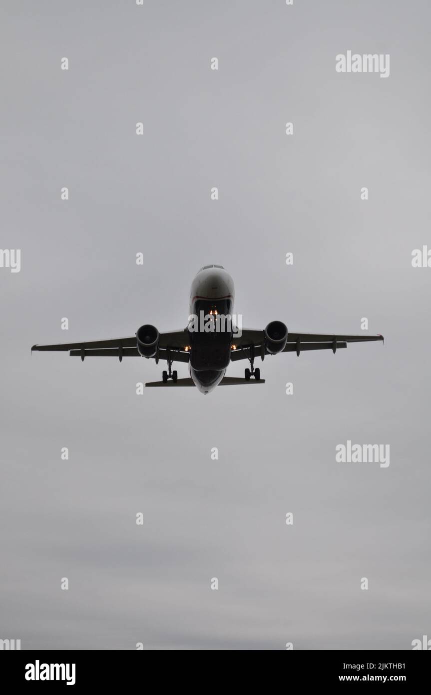 A vertical low angle grayscale shot of a plane flying in the sky Stock ...