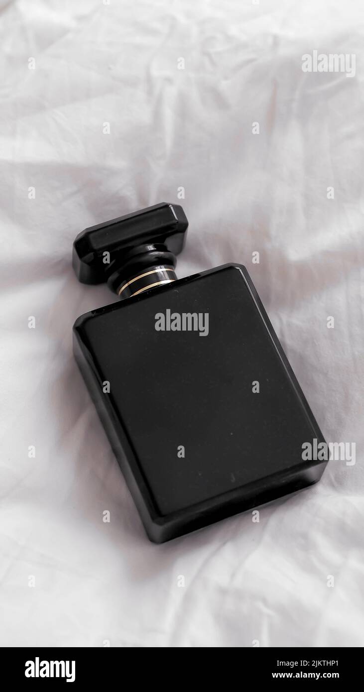 A vertical closeup of a black rectangular perfume bottle on a white ...