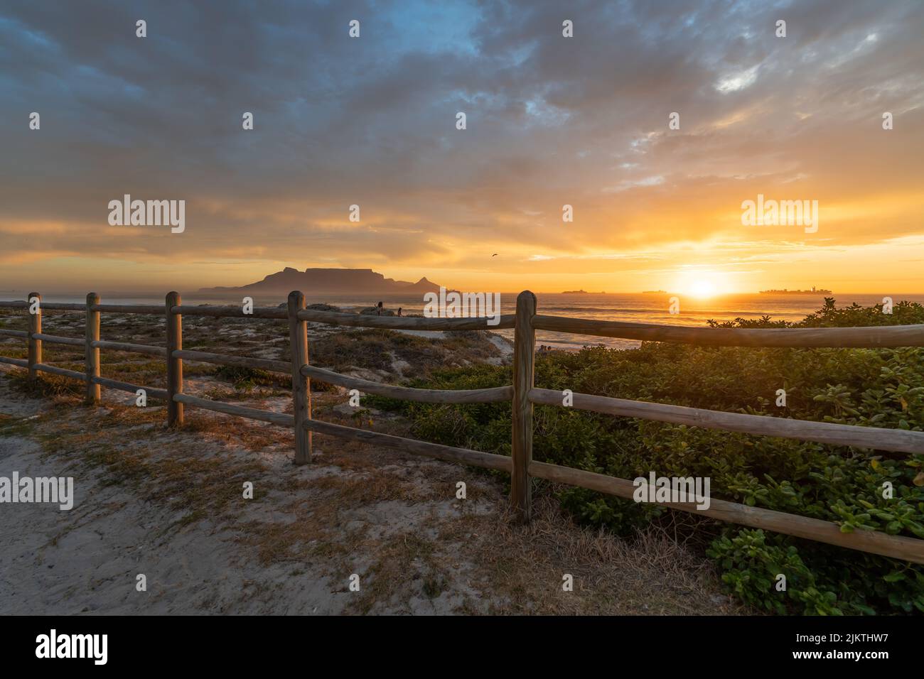 A view of the golden sun setting in a deep blue cloudy sky from behind ...